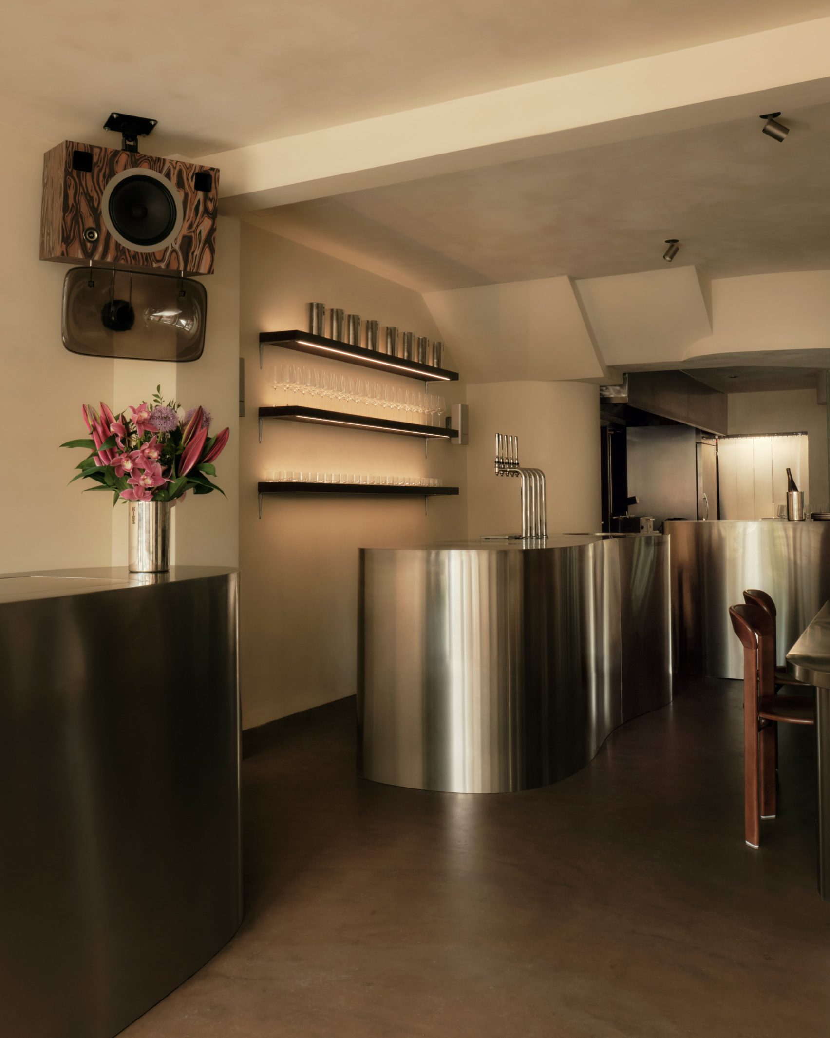 Curving communal table forms "archipelago of steel" at Kiez Kebab